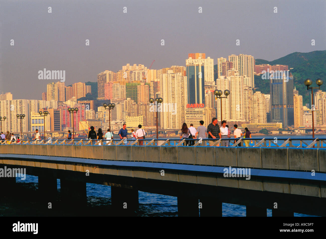 People walking on the promenade in kowloon harbour view of Causeway bay ...