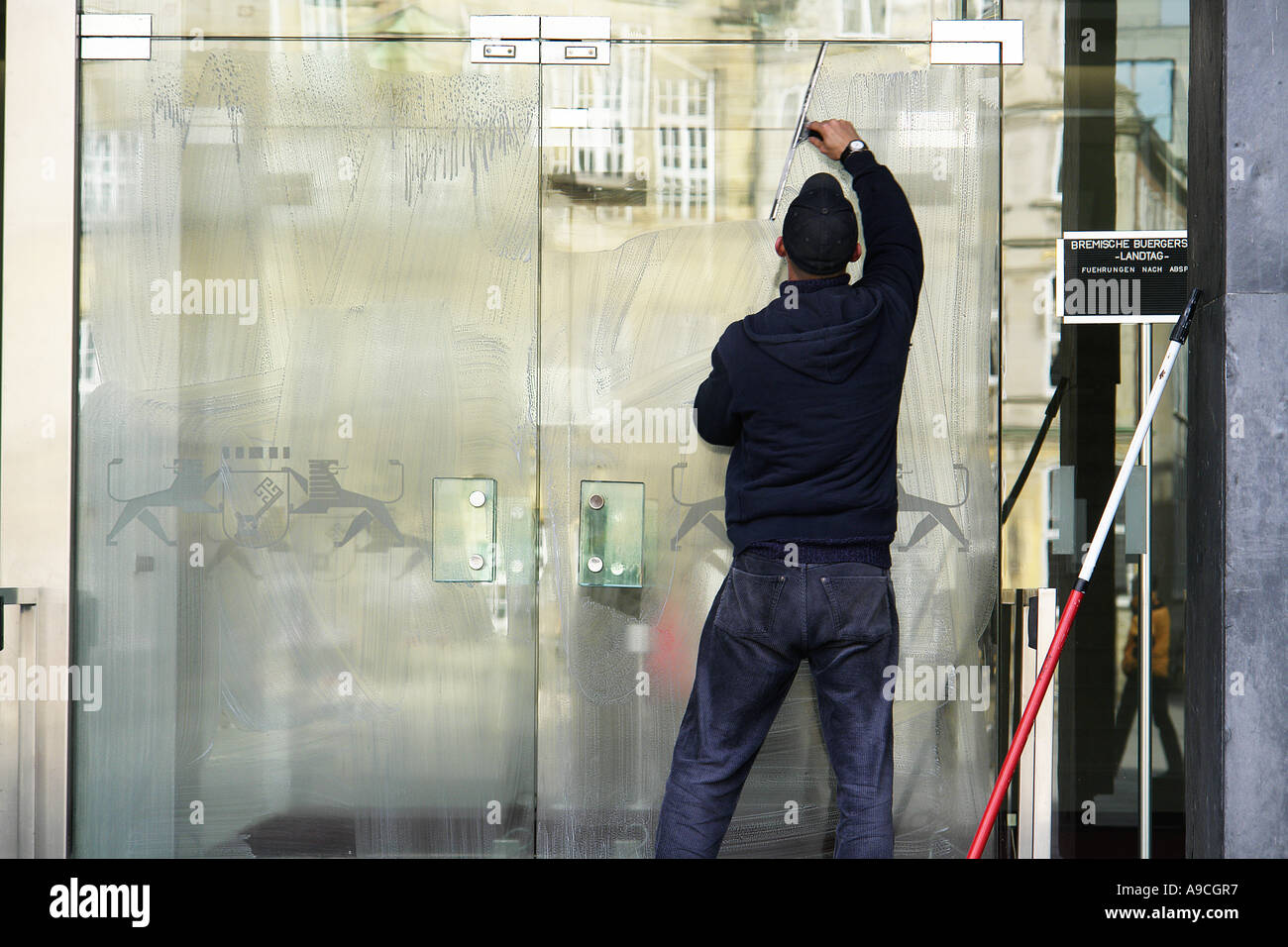 Worker clean glass door Stock Photo - Alamy