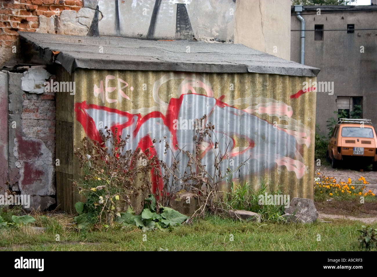 Graffiti and weeds on corrugated metal storage building. Lodz Poland ...