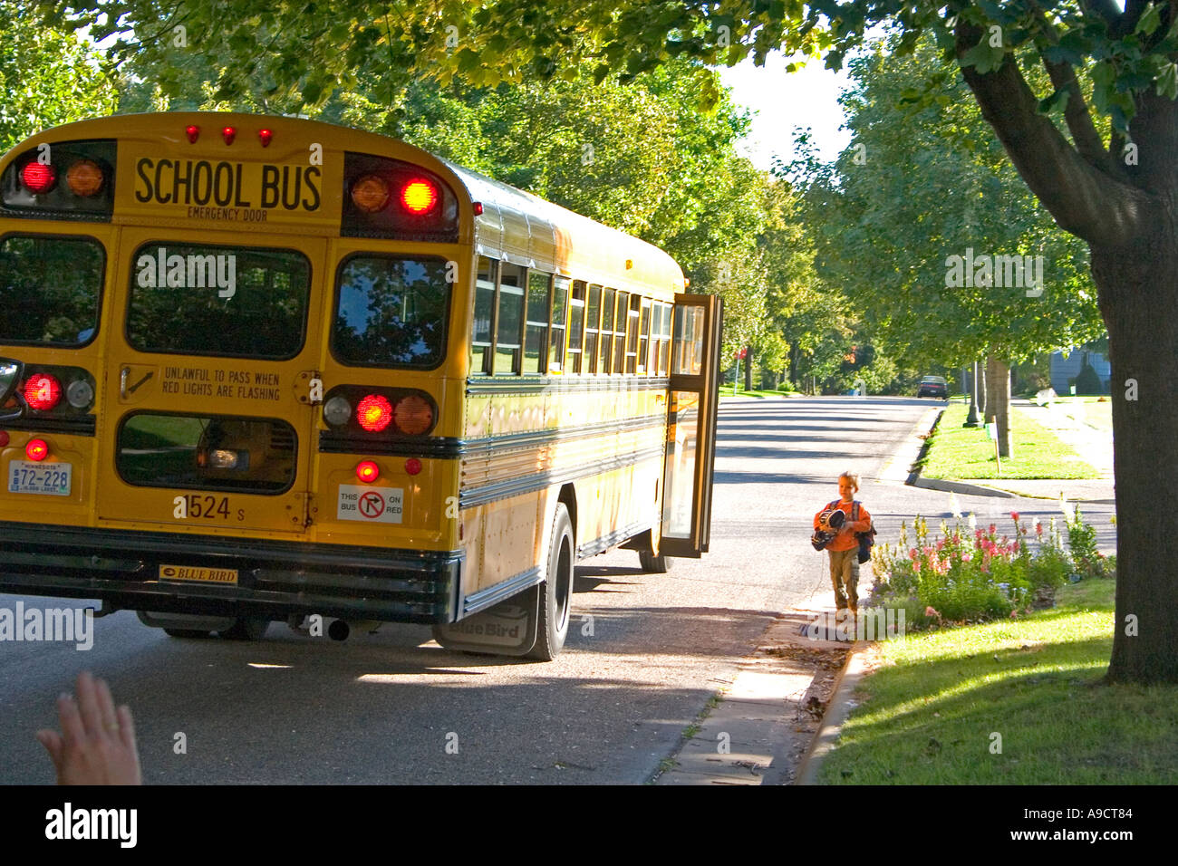 Boy waiting at curb for mom to pick him up after school bus ride. St ...
