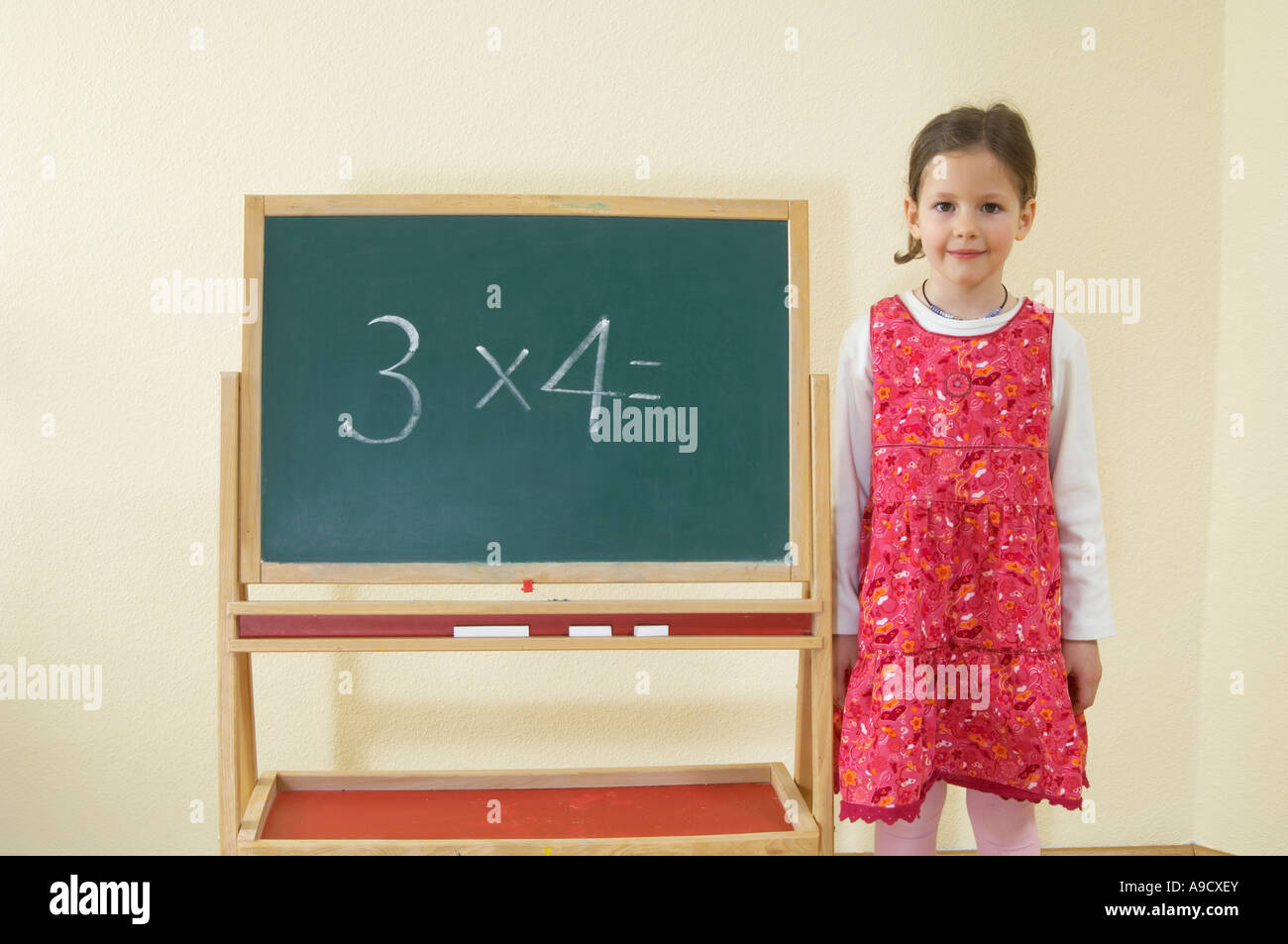 portrait of little girl standing at blackboard with calculating problem ...