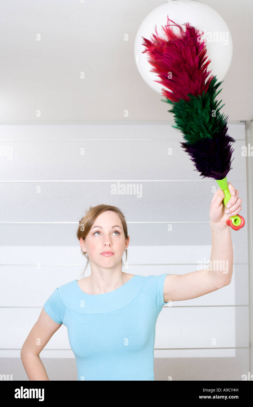 young woman dusting lamp with feather duster Stock Photo - Alamy