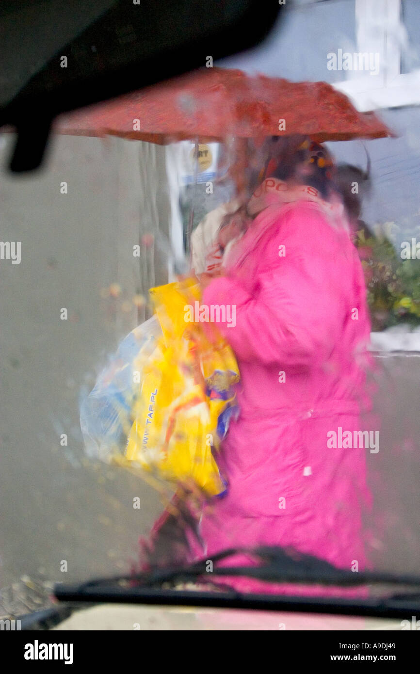 Shopper leaving grocery store with umbrella in the rain. Rzeczyca ...