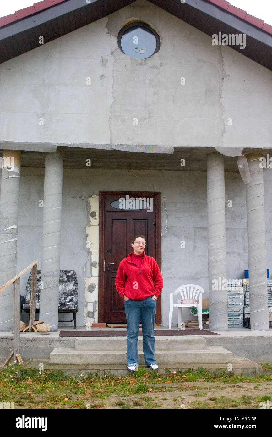 Happy Polish woman standing in front of her unfinished country home ...