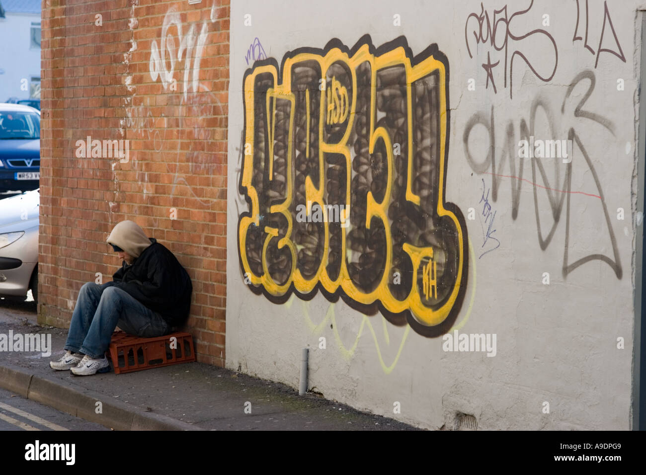 Homeless man squatting in an alleyway underneath a freshly painted ...