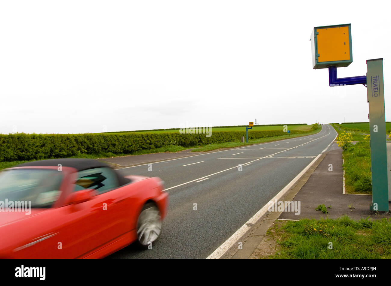 Blurred red sports car passing a roadside speed camera UK Stock Photo ...