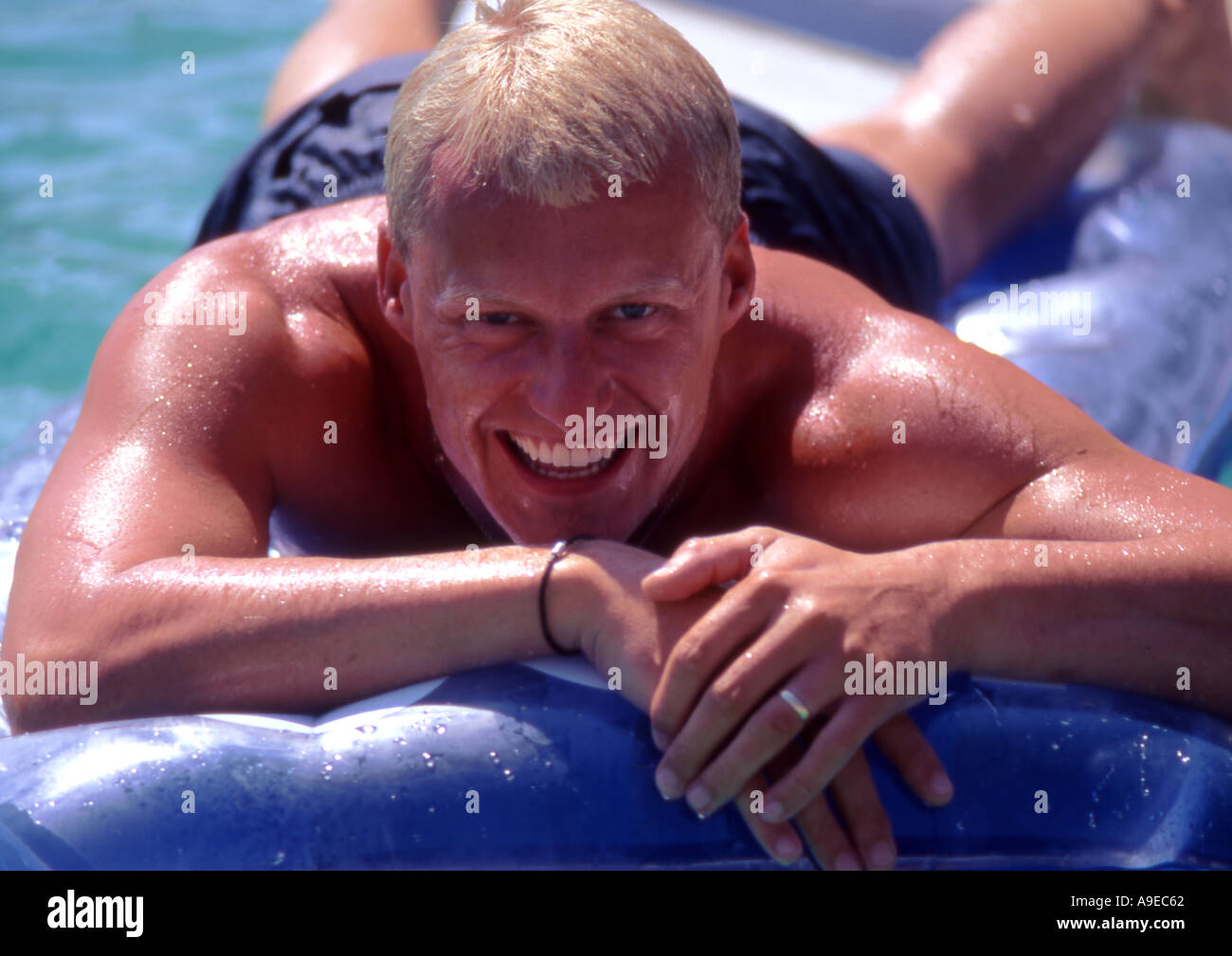 Young man floating on lilo in pool smiling at camera Stock Photo - Alamy