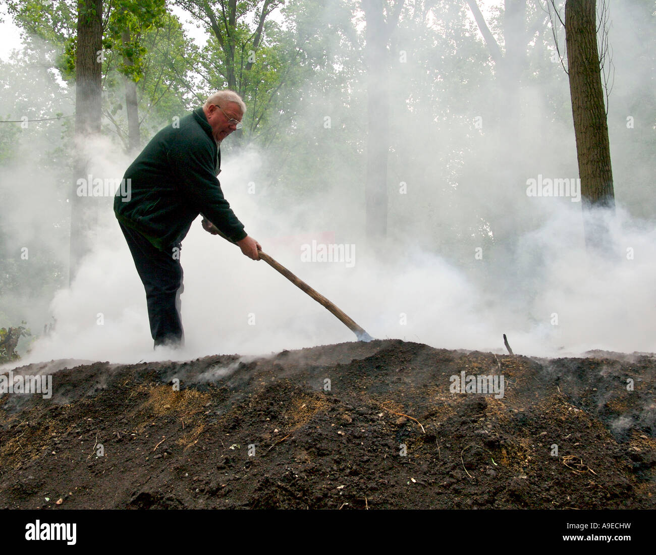Craftsman working on a heap of wood covered with humus soil produces ...