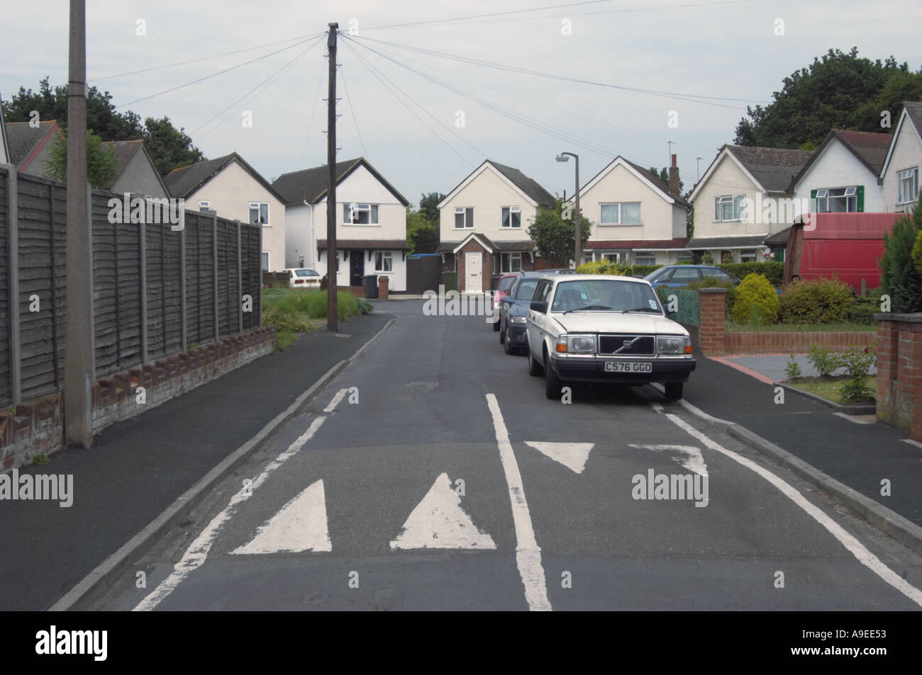Suburban street with road markings, parked cars and housing in ...
