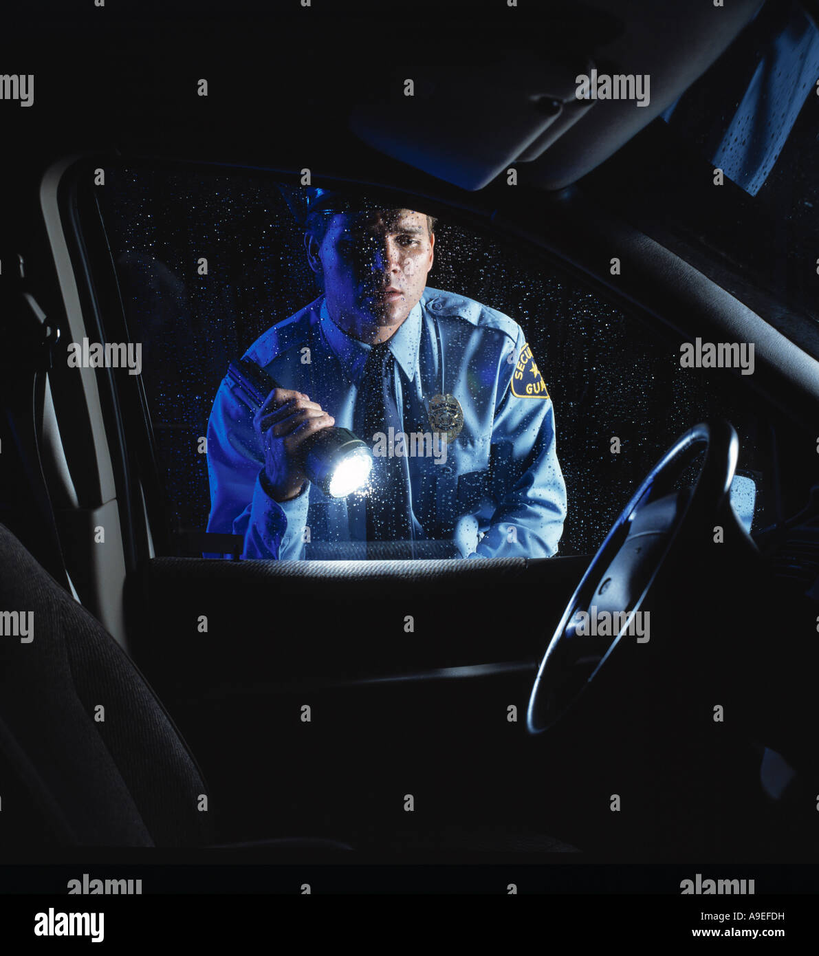 A security guard inspects an auto interior on a rainy night Stock Photo ...
