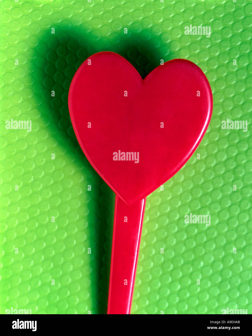 RED PLASTIC HEART WITH GREEN BACKGROUND Stock Photo - Alamy