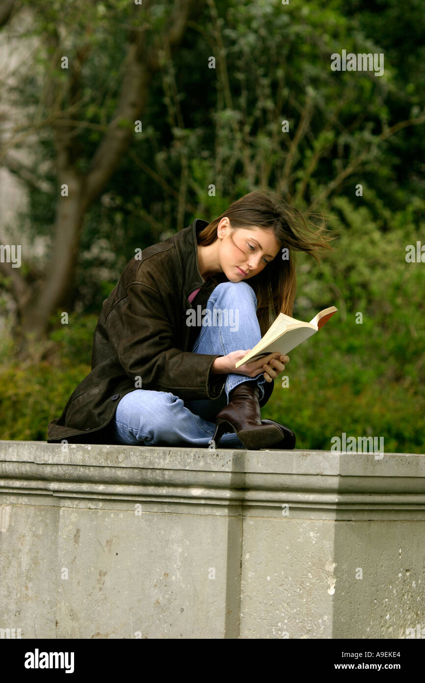 Young woman reading a book on a stone plinth Relaxing Stress relief ...