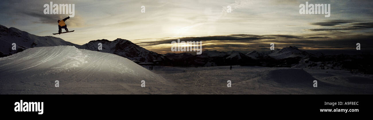 panoramic dusk image of snowboarder jumping off ramp flash trick grab ...