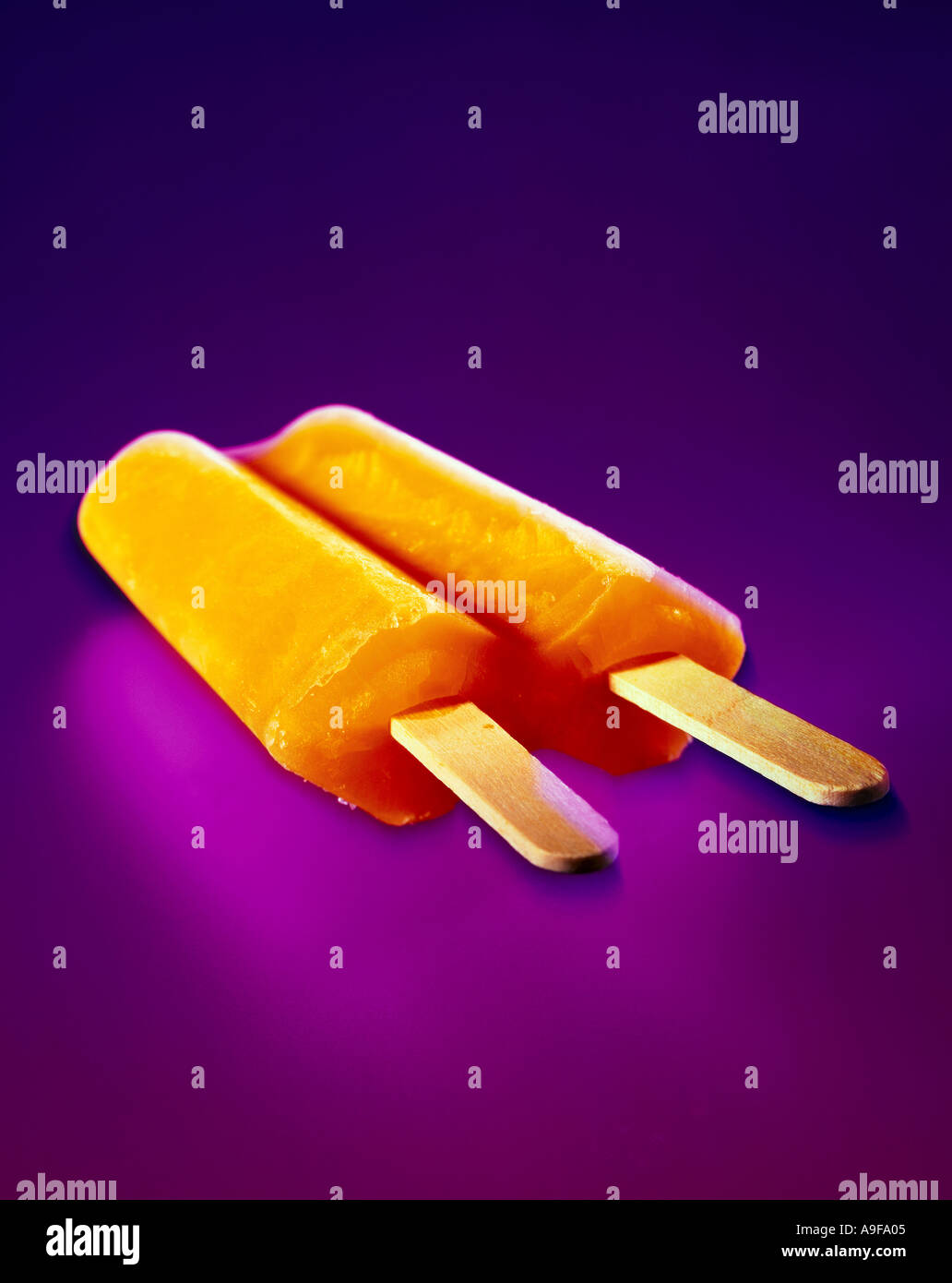 orange twin Popsicle on purple background Stock Photo - Alamy