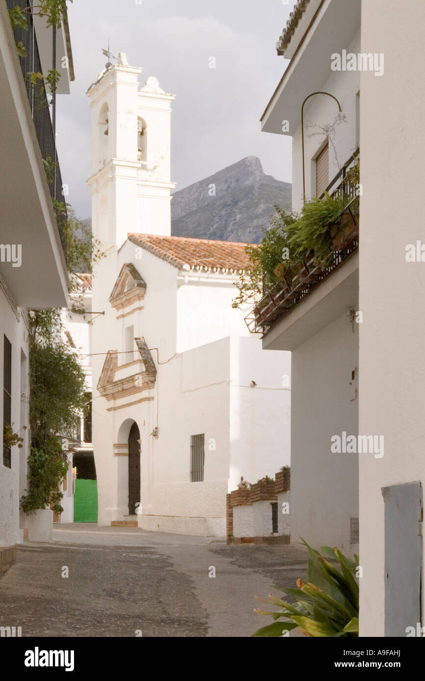 A typically narrow street and church in the hill village of Istan Spain ...