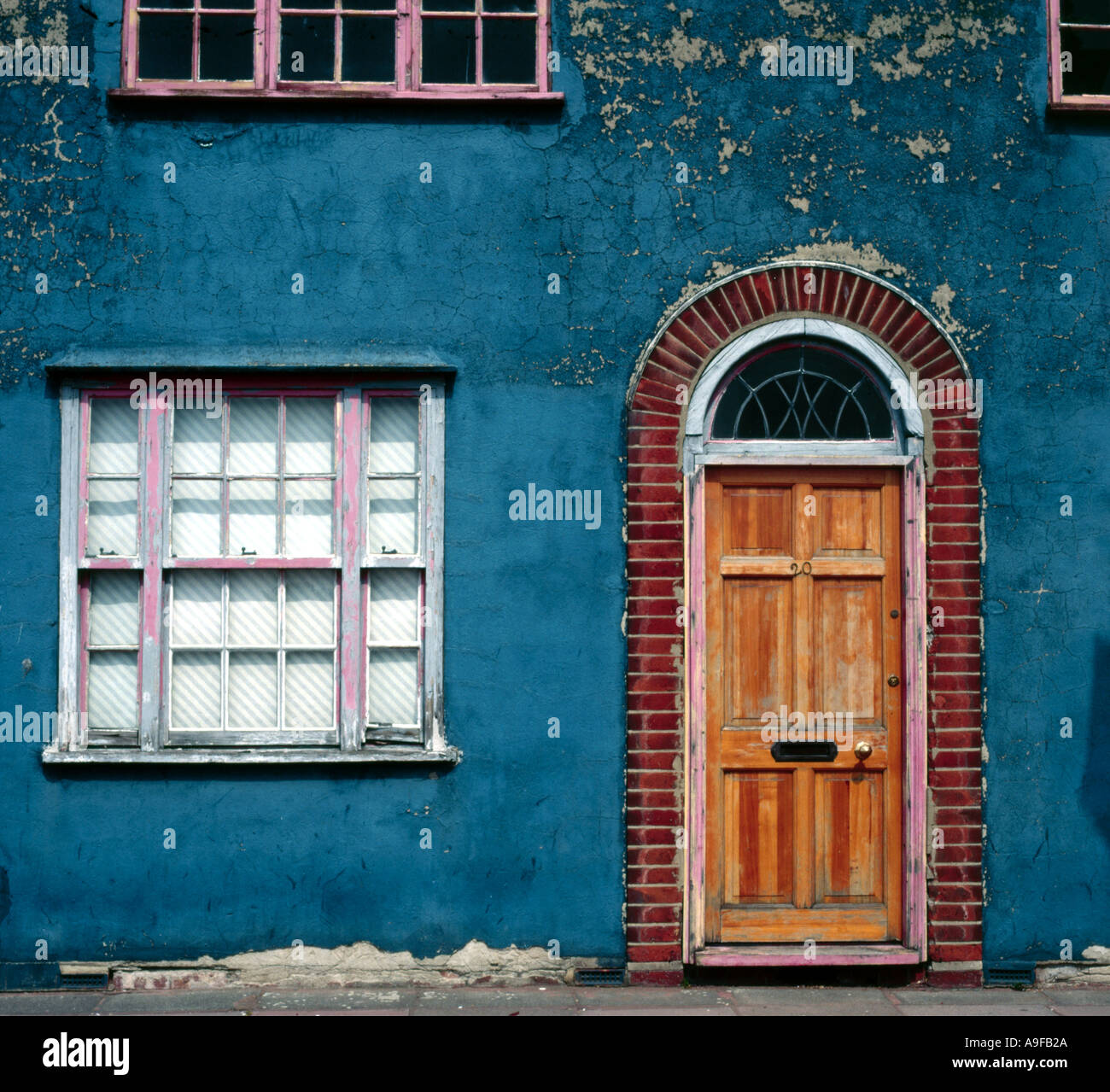 Old house with peeling blue walls and pink window frames Stock Photo ...
