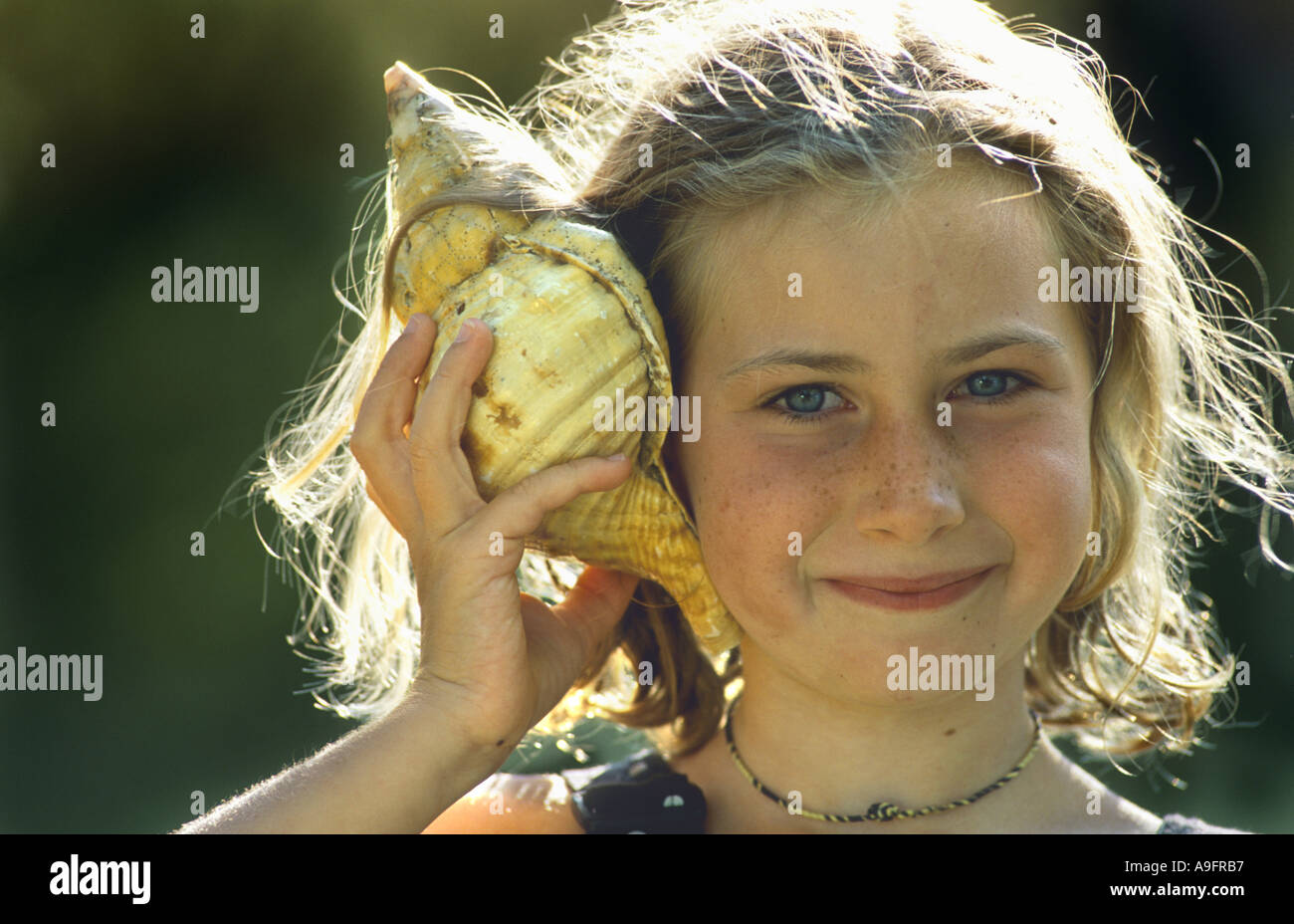 girl holding shell at her ear Stock Photo - Alamy