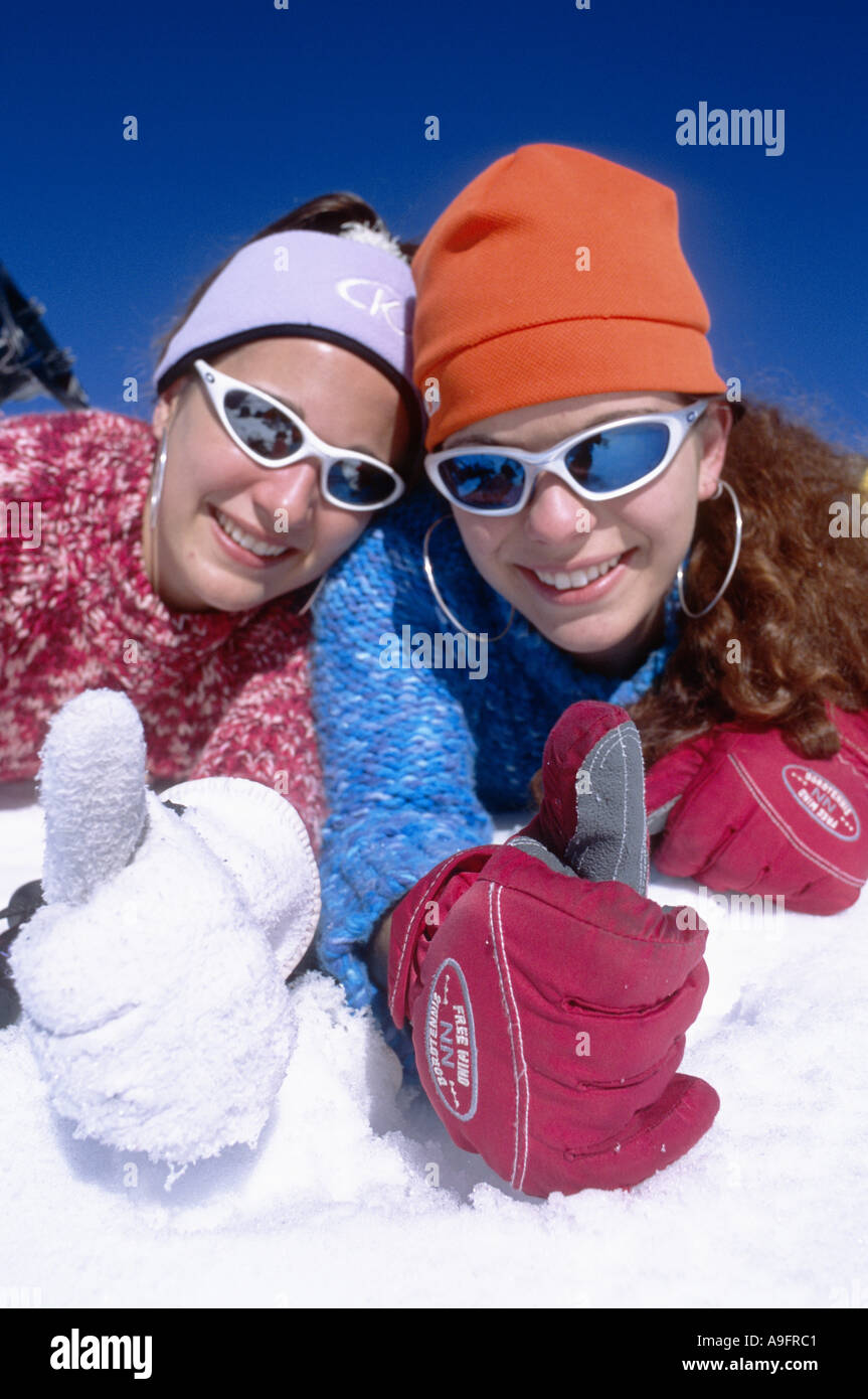 two girls lying in snow, wearing caps, thumbs up Stock Photo - Alamy