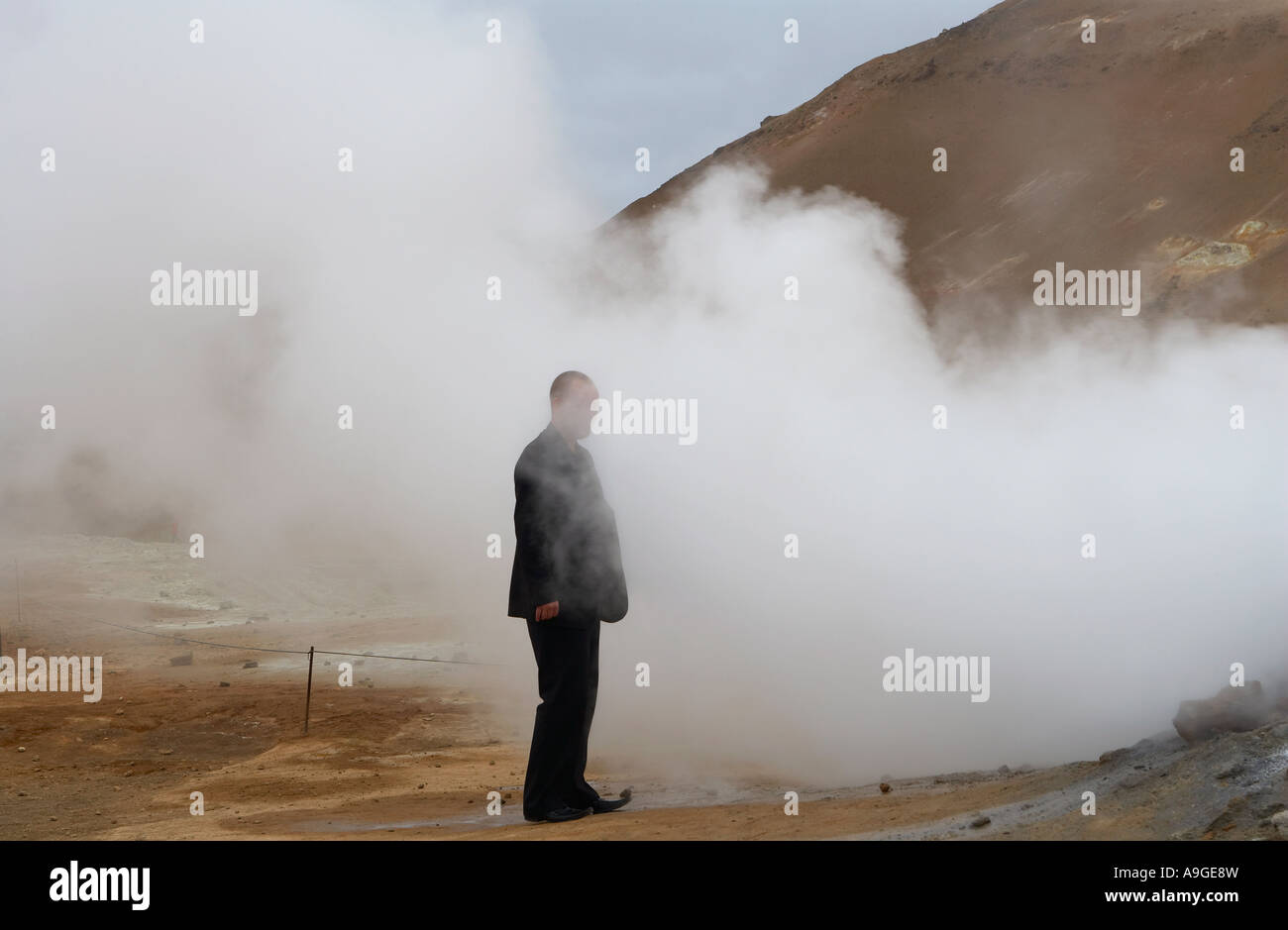 Man in a suit standing in the steam from a small Geyser Stock Photo - Alamy