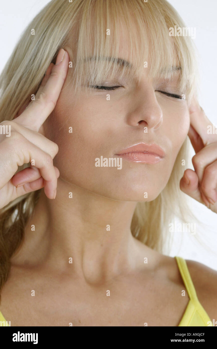 blond woman with closed eyes, touching temples with her hands, face ...