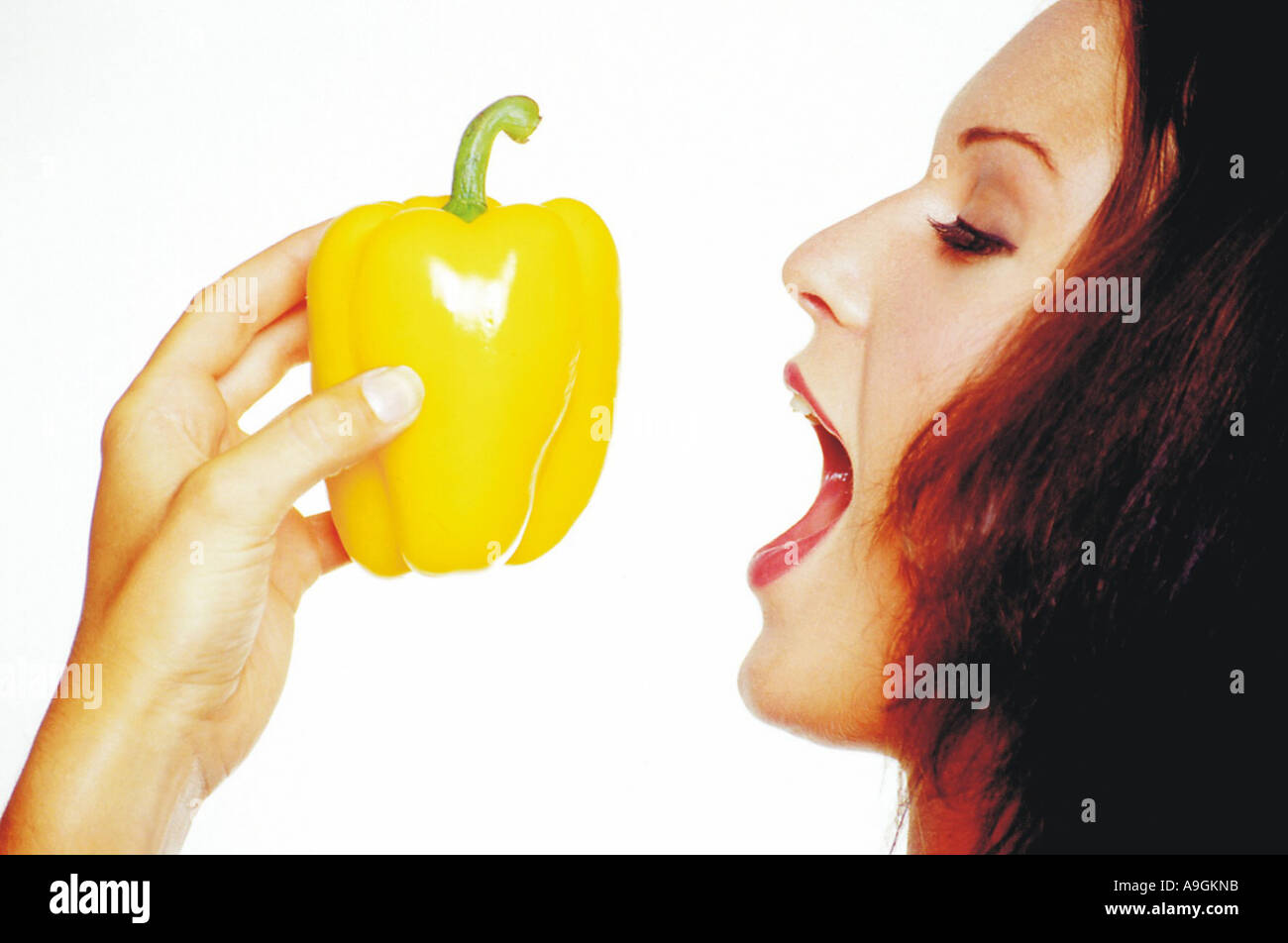 darkhaired young woman biting a chili pepper Stock Photo - Alamy