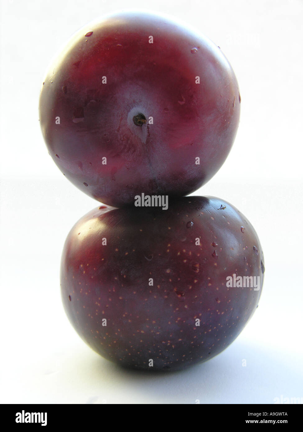 two plums on a pale background Stock Photo - Alamy