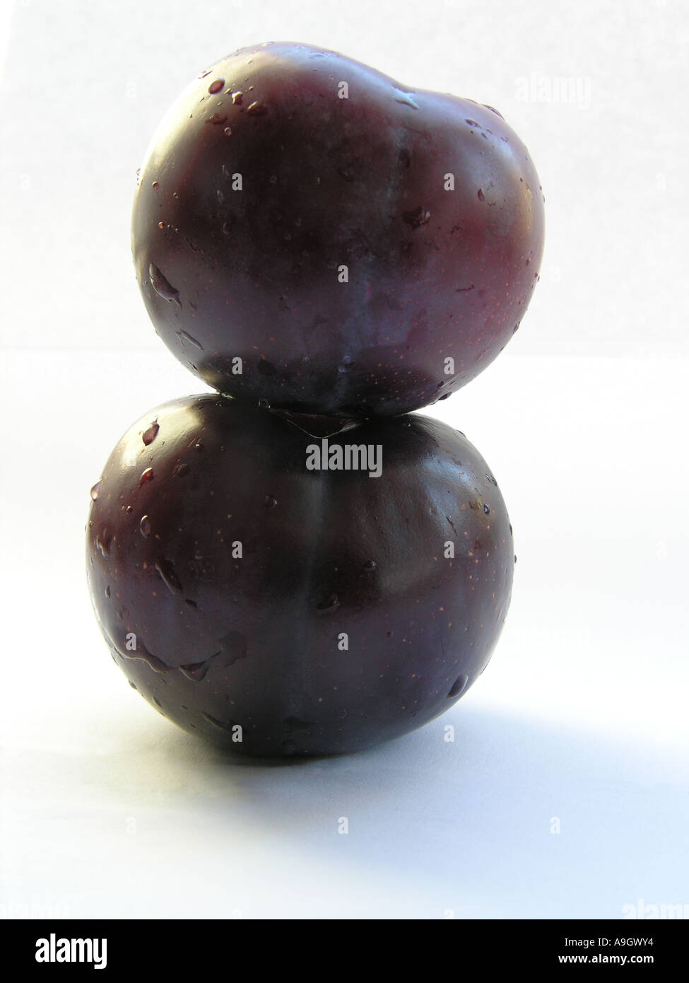 two plums on a pale background Stock Photo - Alamy