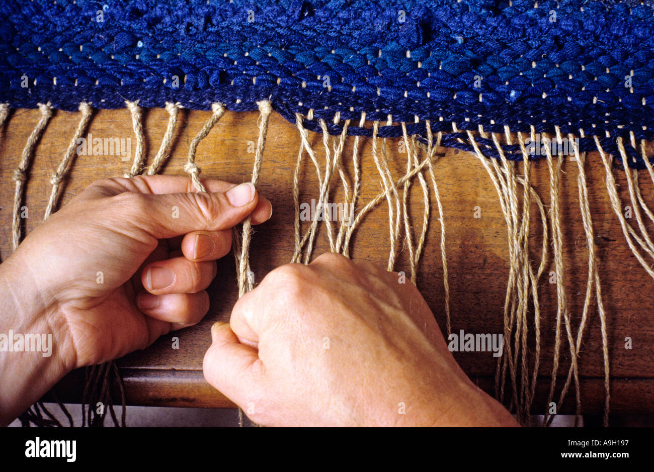 Tying and twisting the ends of a rag rug Stock Photo - Alamy