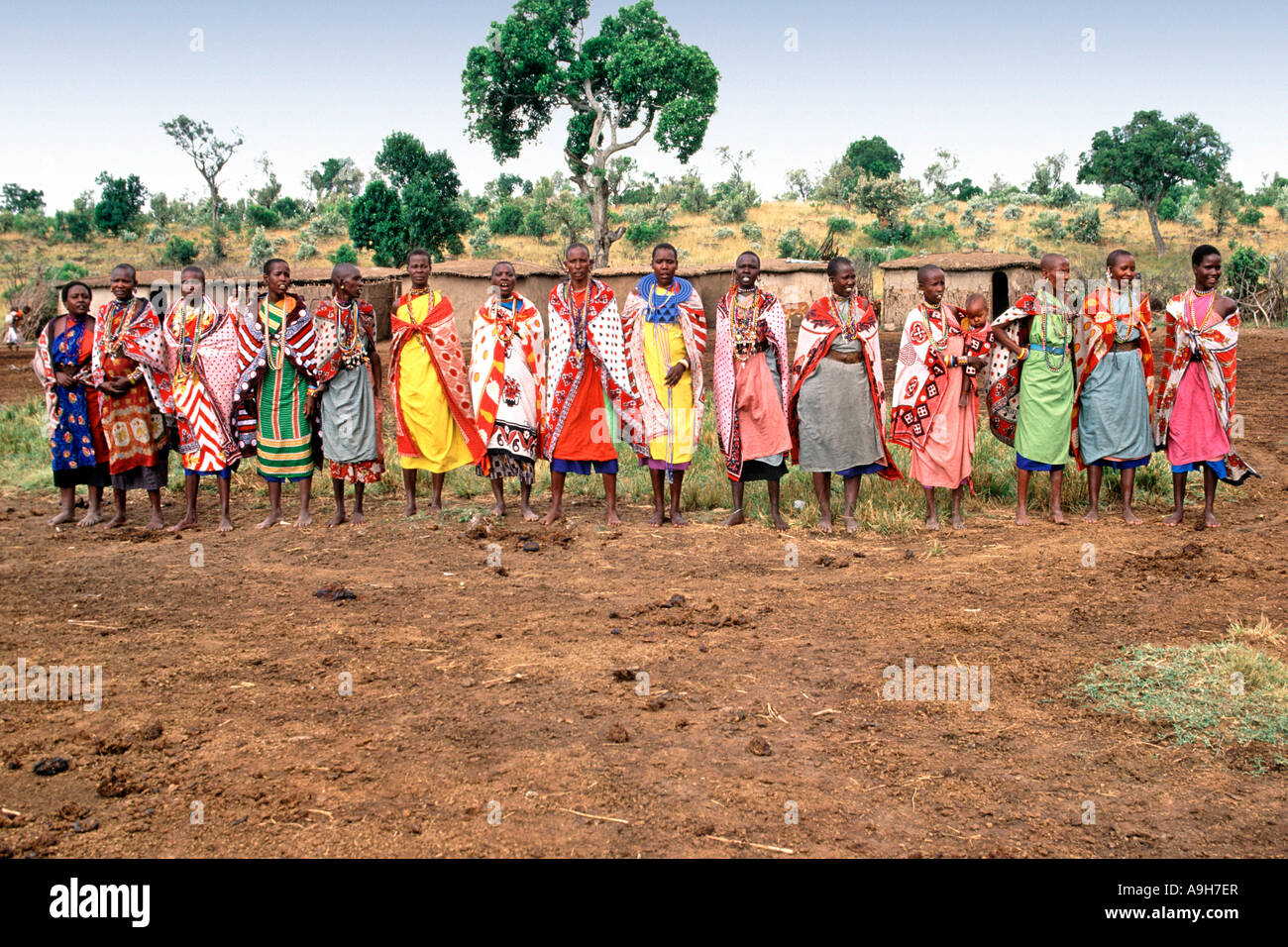 Masai women perform a traditonal welcome for tourists visiting their ...