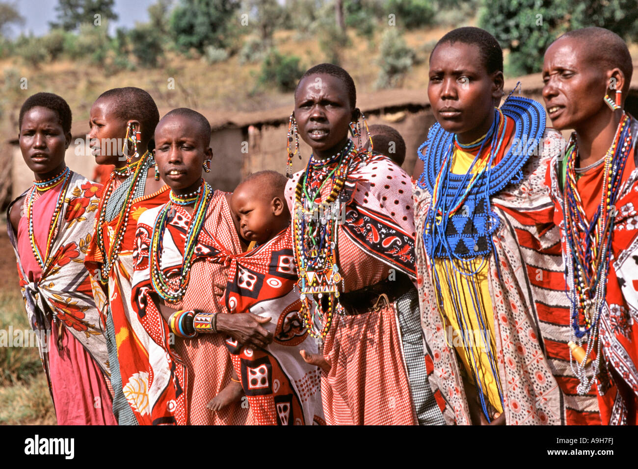 Masai women perform a traditonal welcome for tourists visiting their ...