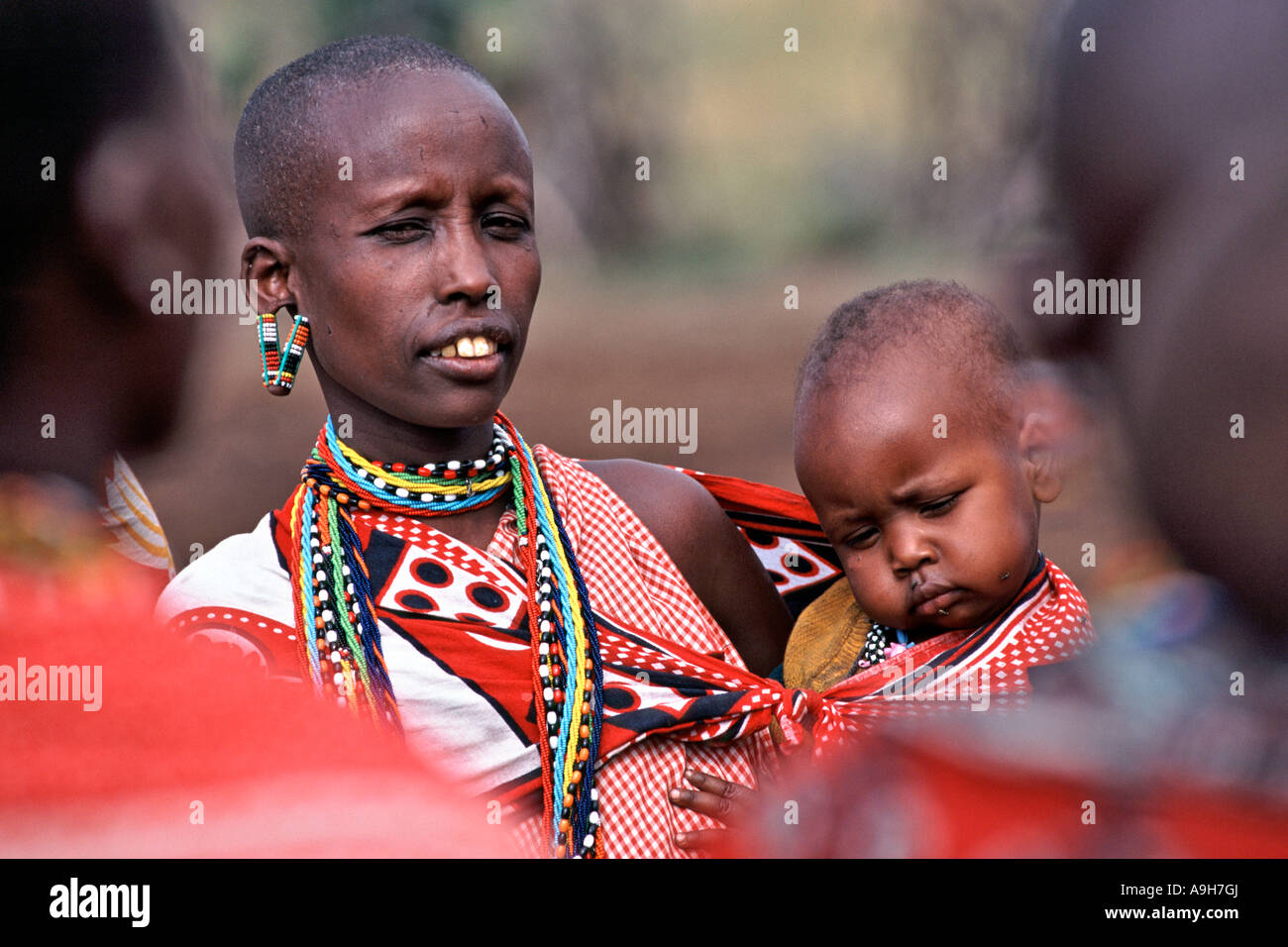 A Masai woman and her baby in their village manyatta in the Maasai Mara ...