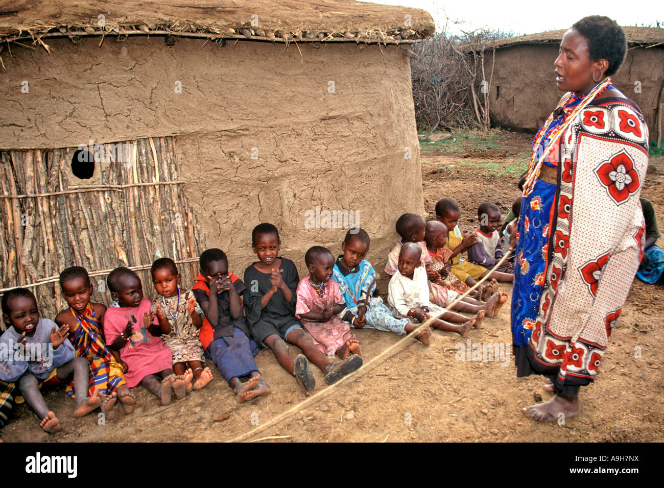 A Maasai lady teaching a group of children in their village (called a ...