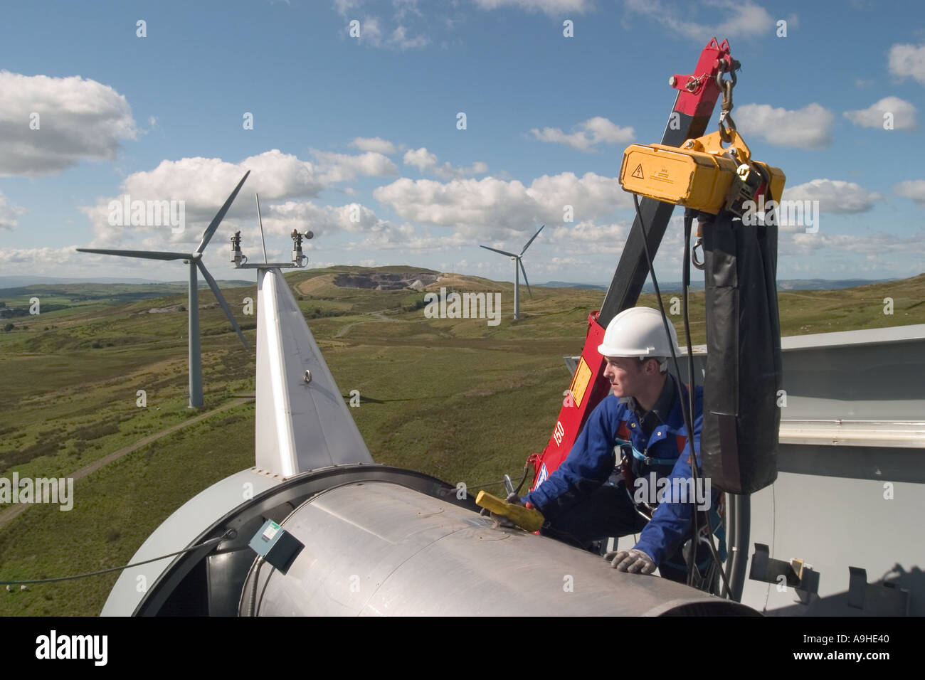 Engineer working on top of nacelle during maintenance of industrial wind power turbine at ...