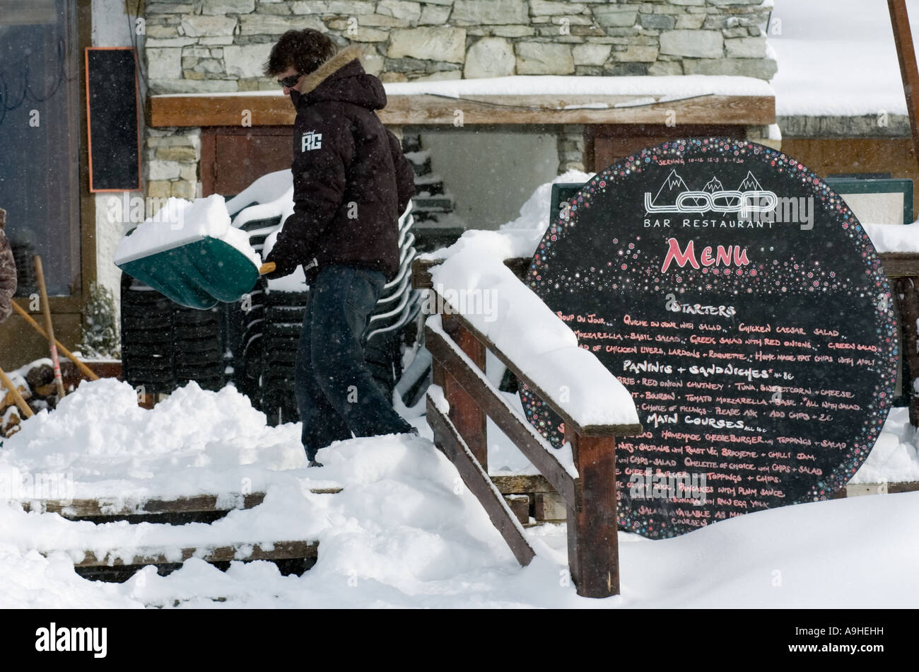 Clearing snow from a cafe balcony after a snowfall at Tignes Savoie ...