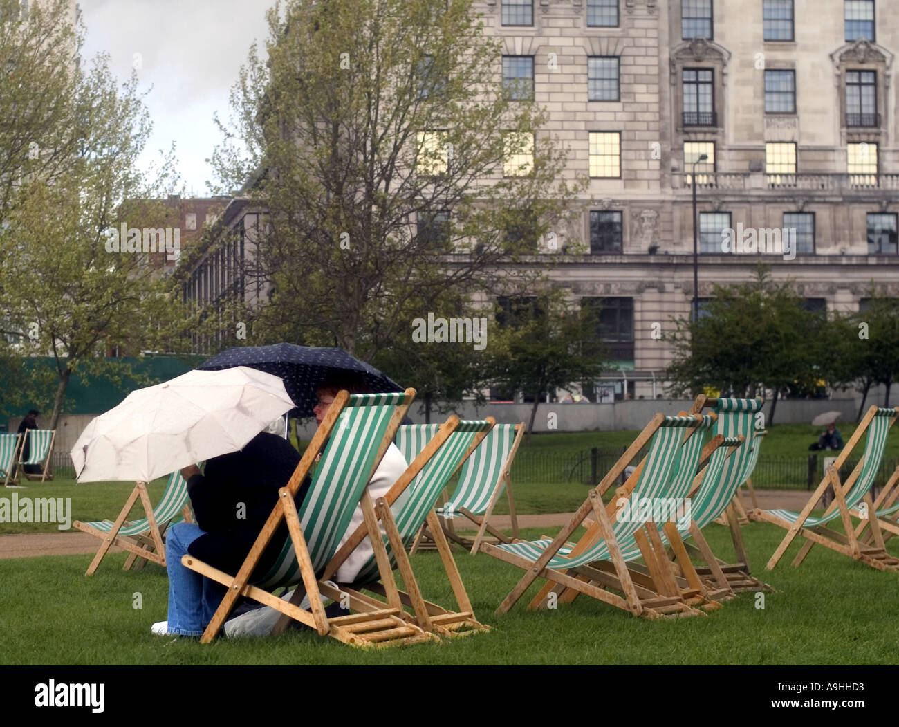 two women sit in deck chairs in Green park in the rain Stock Photo - Alamy