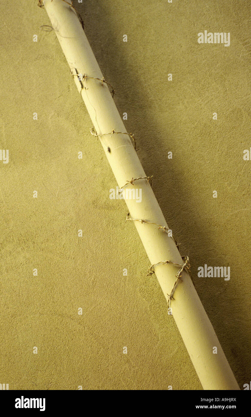 Pipe on side of building wrapped in barbed wire Stock Photo - Alamy