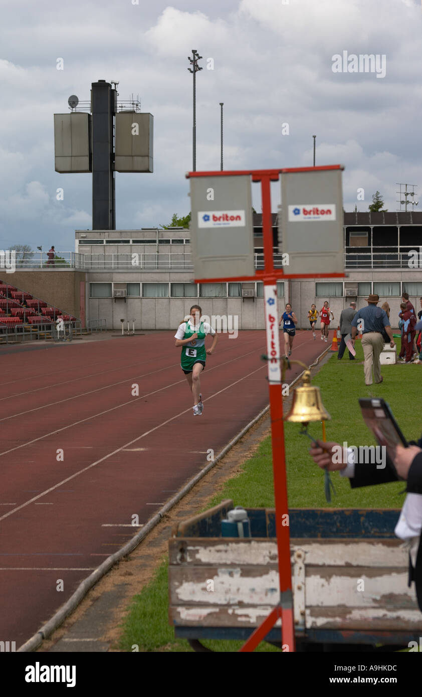 Athletes running on a track coming up to the bell Stock Photo - Alamy