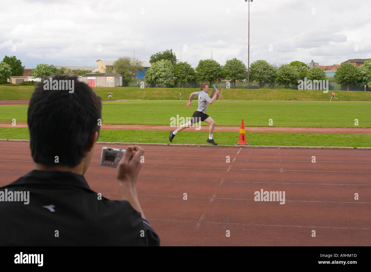 Young male athletes in relay race holding baton being photographed by a ...