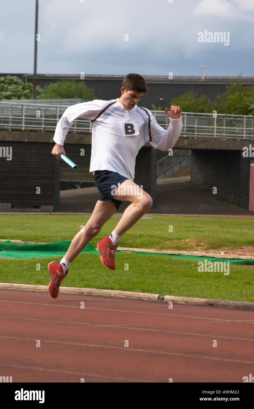 Young male athletes in relay race holding baton Stock Photo - Alamy