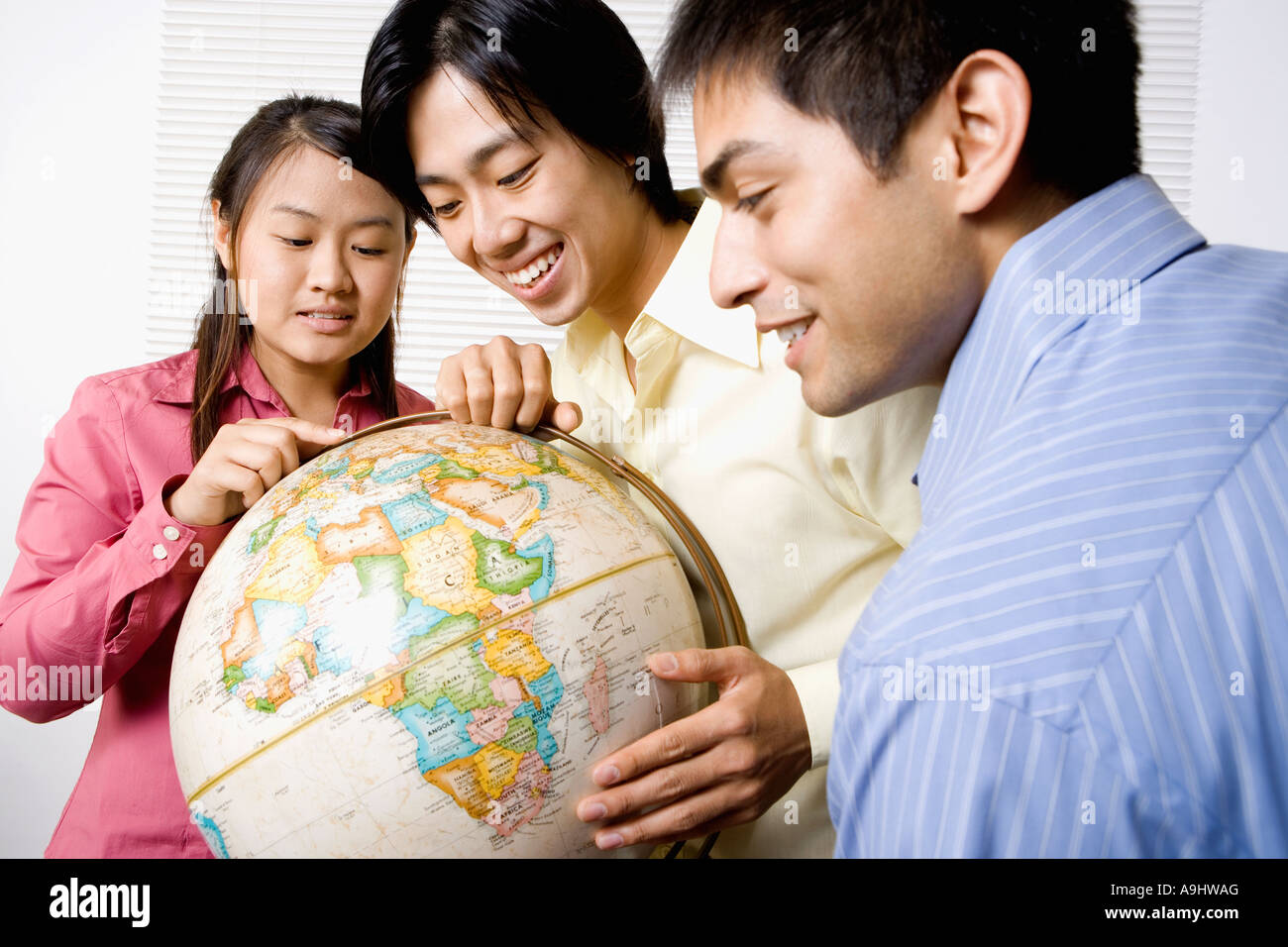 Three friends looking at globe Stock Photo - Alamy