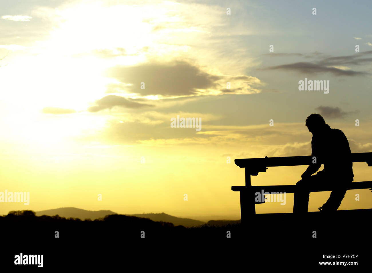 man is sitting on the bench, and watching sunset Stock Photo - Alamy