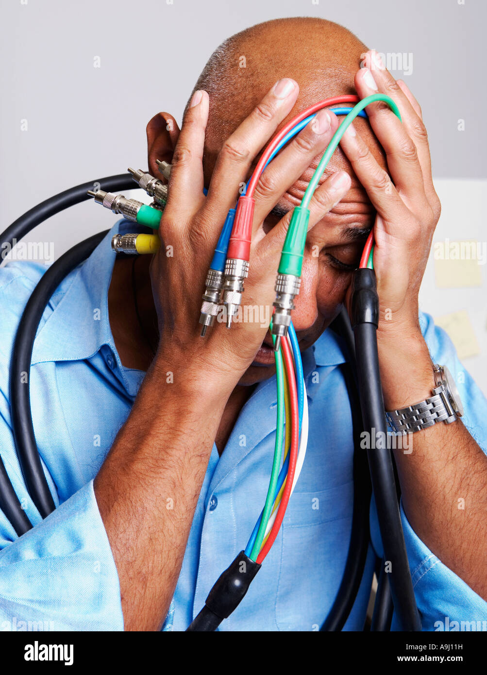 African businessman holding computer cables with head in hands Stock ...