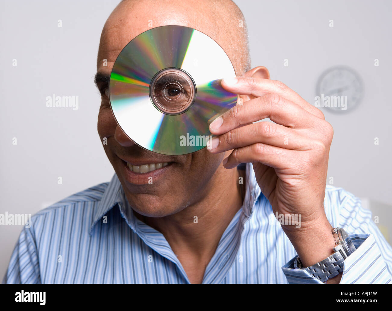 African businessman looking through middle of cd Stock Photo - Alamy