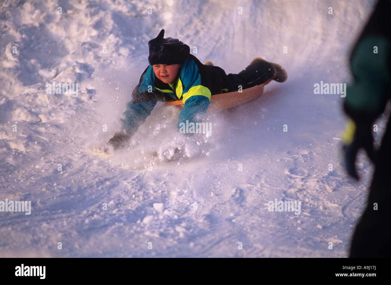 USA Alaska Eskimo boys sledding on hills above Bering Sea ice outside ...