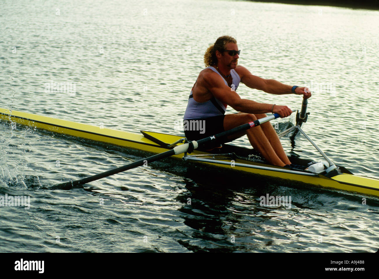 A man rowing a single scull rowboat Stock Photo - Alamy
