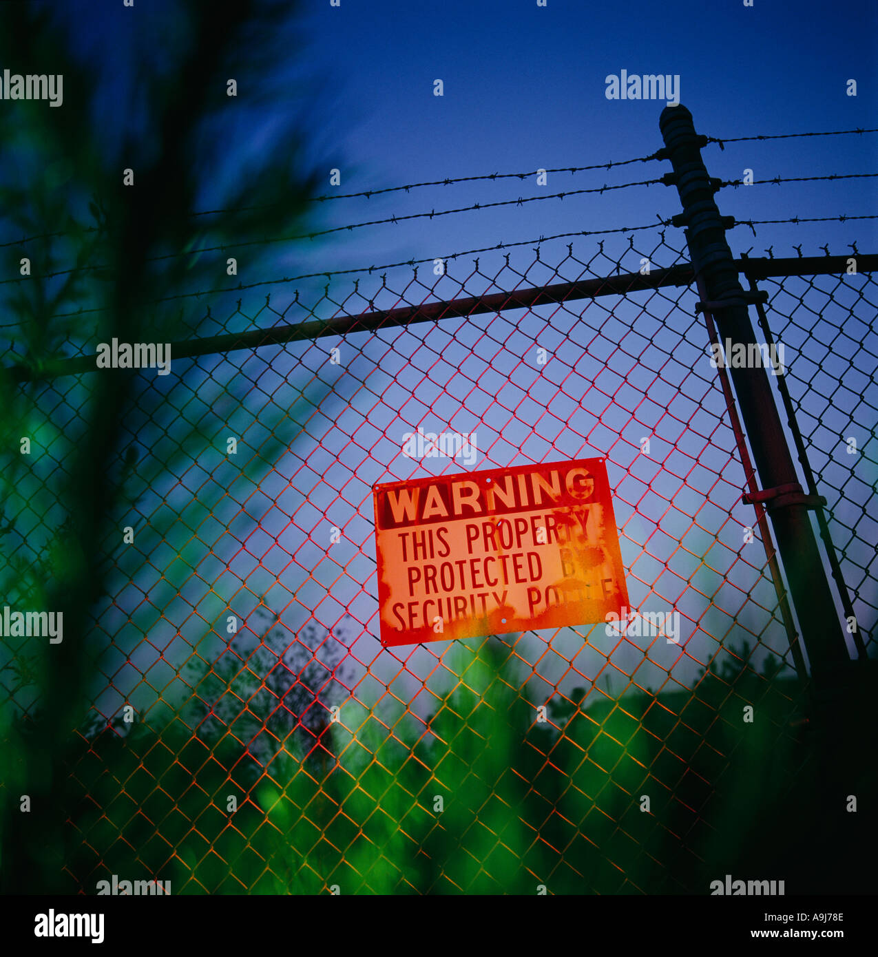 Warning sign on chain link fence with barbed wire Stock Photo - Alamy