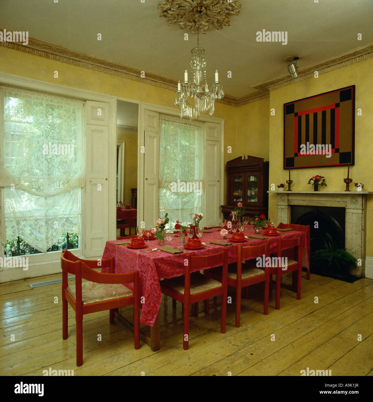 Lace curtains at tall windows of eighties diningroom with red ...