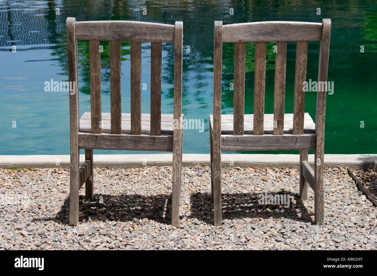 "Wooden chairs facing garden pond Stock Photo - Alamy