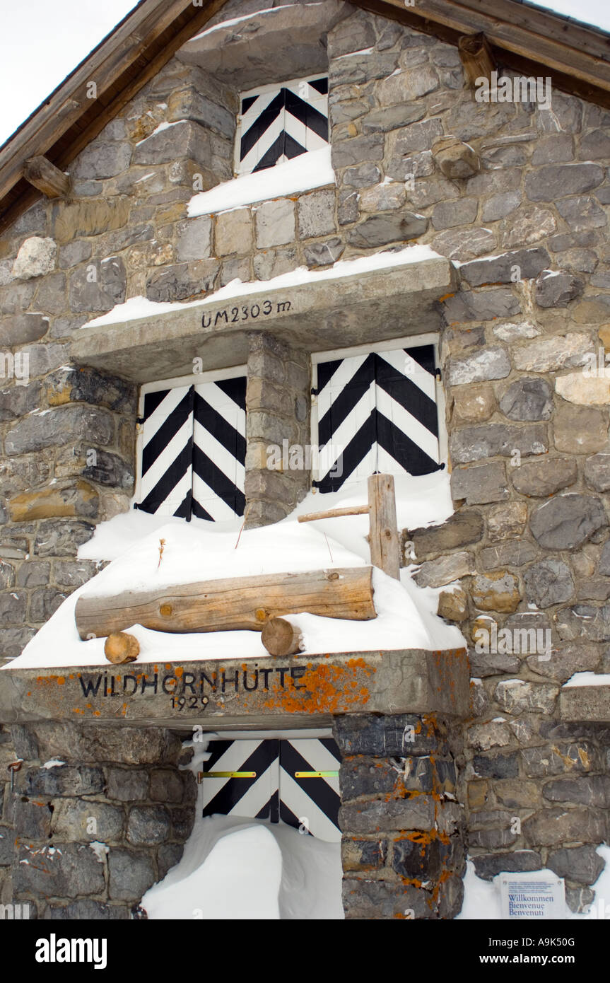 Snow covered frontdoor and black and white window shutters of ...