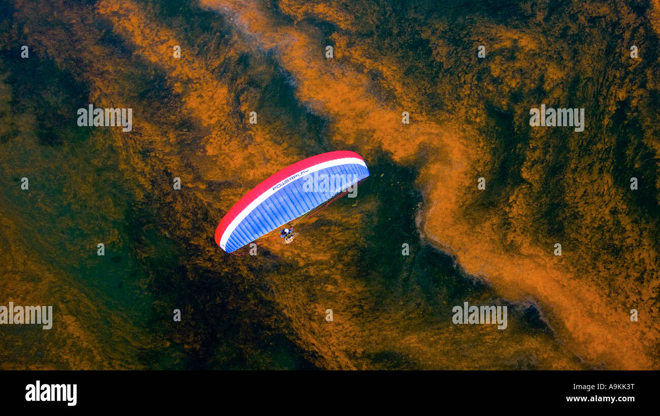Powered paraglider flying over water Stock Photo - Alamy